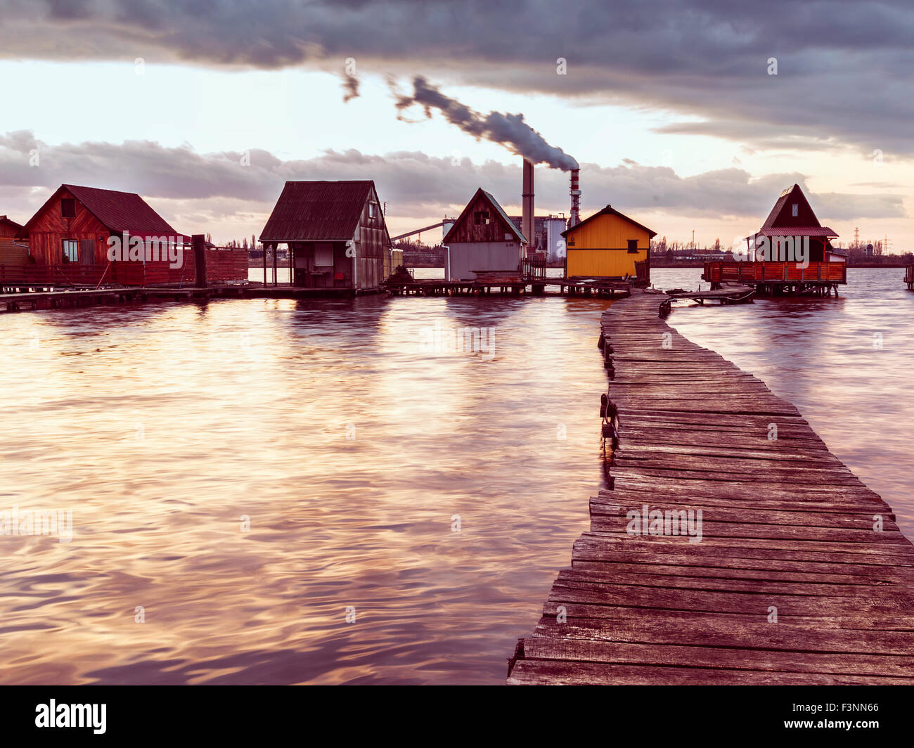 Sunset lake Bokod with pier and fishing wooden cottages, power plant in ...