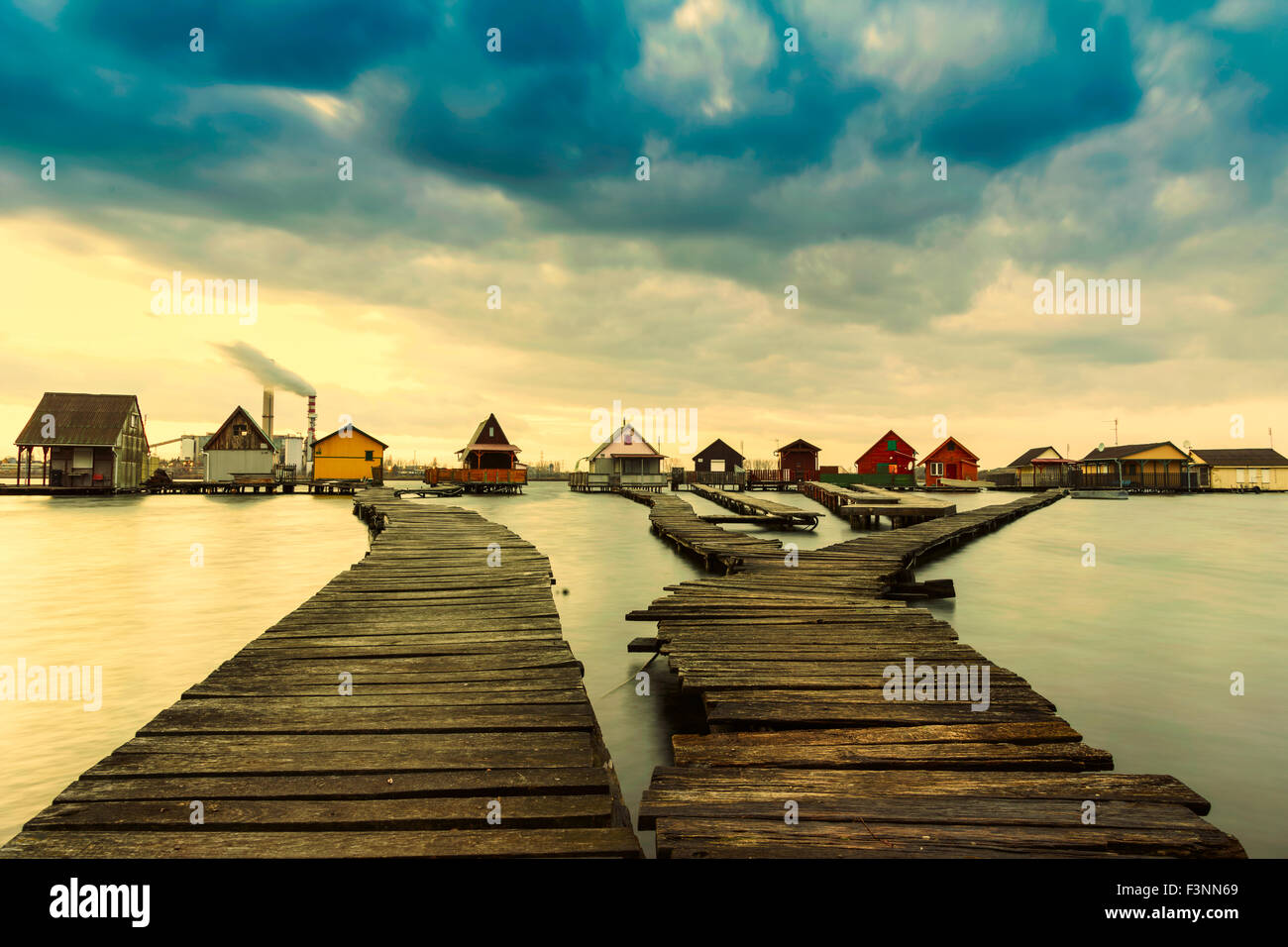 Sunset lake Bokod with pier and fishing wooden cottages, power plant in ...