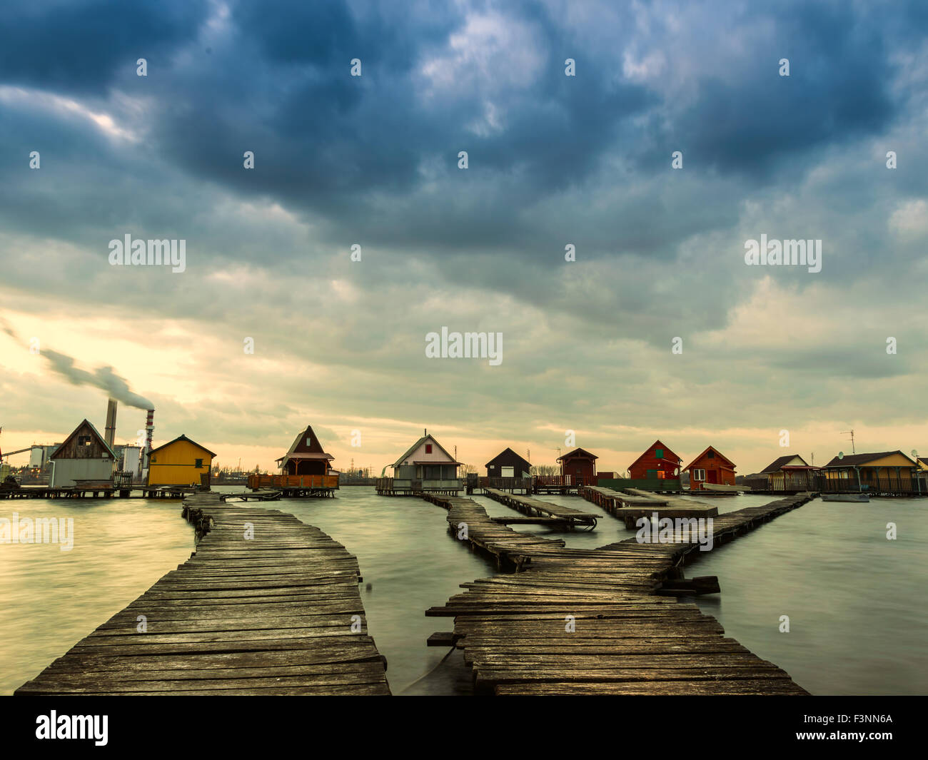 Sunset lake Bokod with pier and fishing wooden cottages, power plant in ...