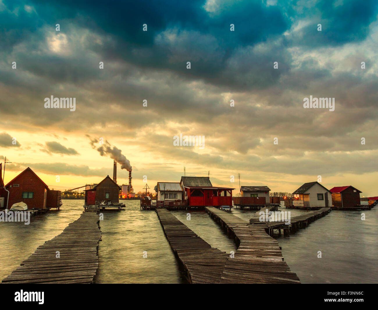 Sunset lake Bokod with pier and fishing wooden cottages, power plant in ...