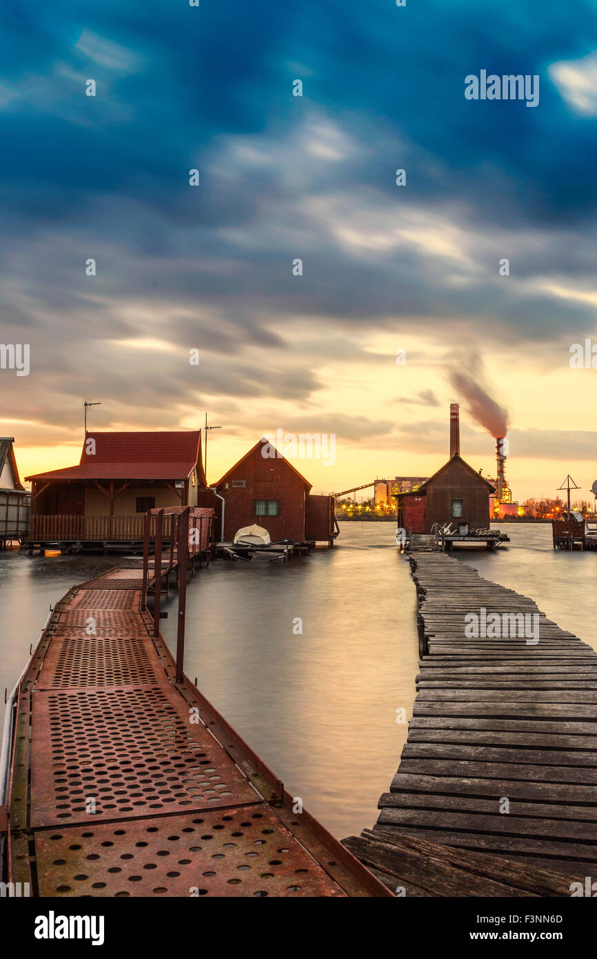 Sunset lake Bokod with pier and fishing wooden cottages, power plant in ...
