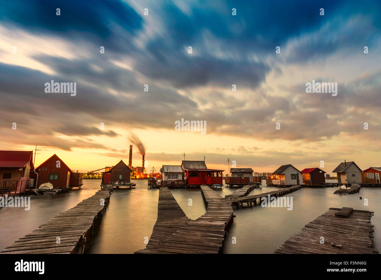 Sunset lake Bokod with pier and fishing wooden cottages, power plant in ...