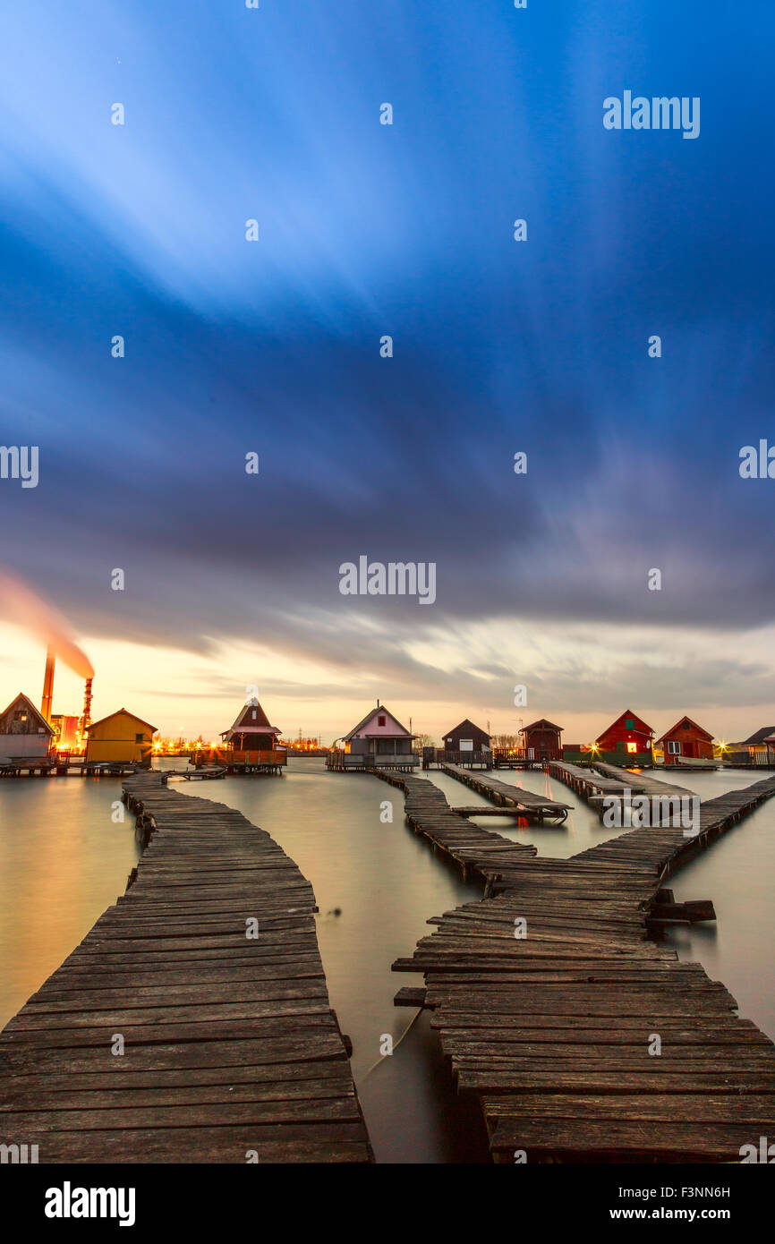 Sunset lake Bokod with pier and fishing wooden cottages, power plant in ...