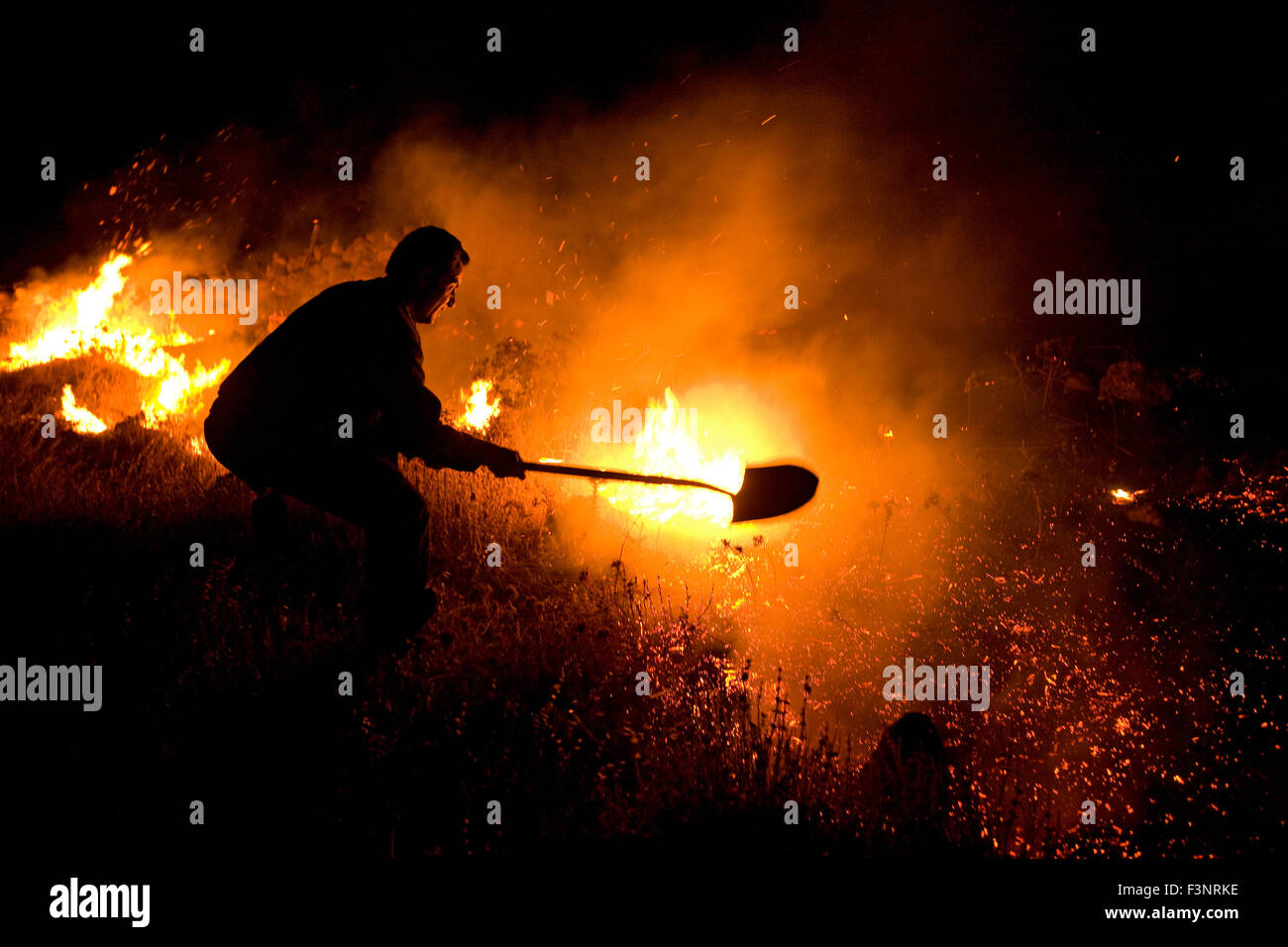 Backlit by burning flame smoke, shilhouette of a fireman, fighting fire ...