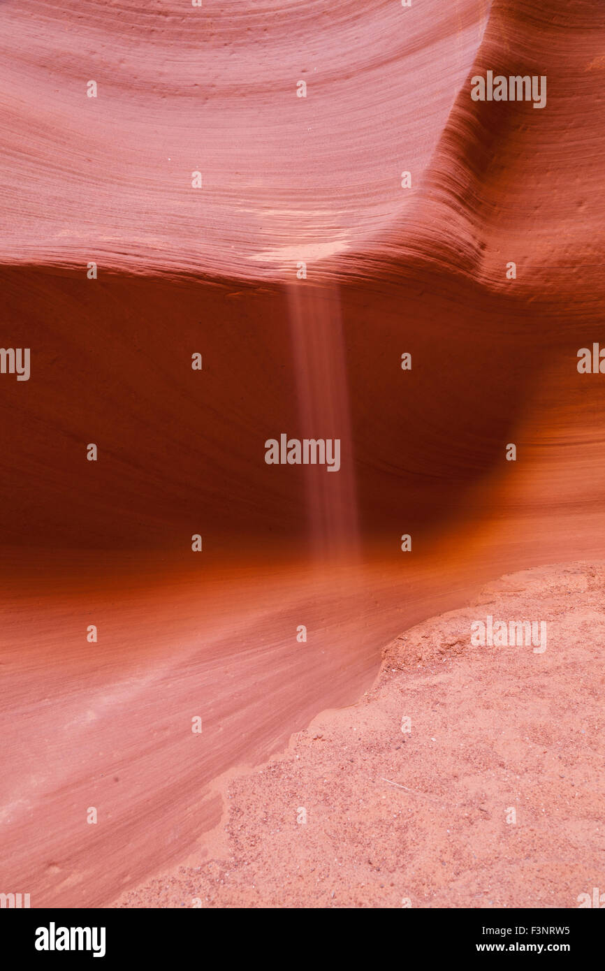 Super fine orange sand cascades off of a small shelf inside of Canyon X ...