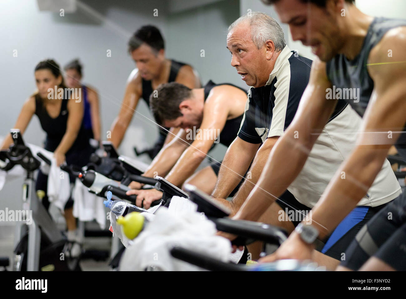 Side view of people riding stationary bicycles during a spinning class ...