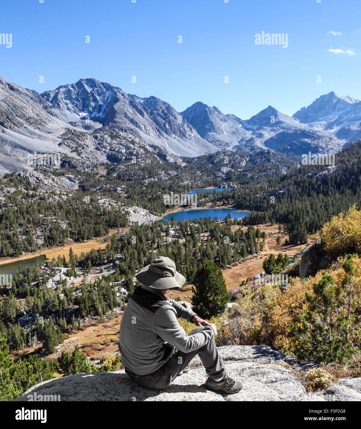 Resting hiker gazes at Little Lakes Valley in Rock Creek Canyon in the ...