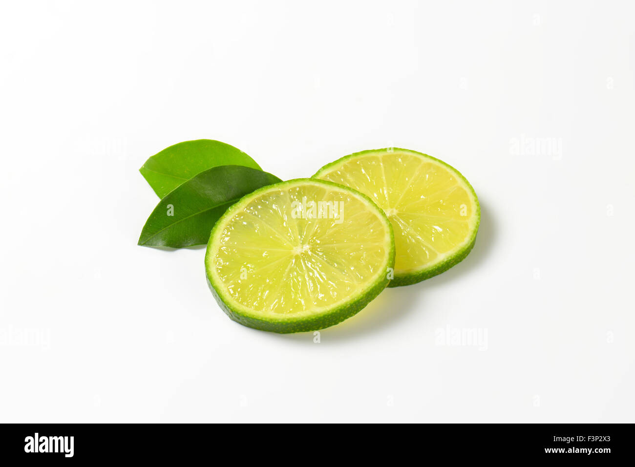 two lime slices with leaves on white background Stock Photo - Alamy