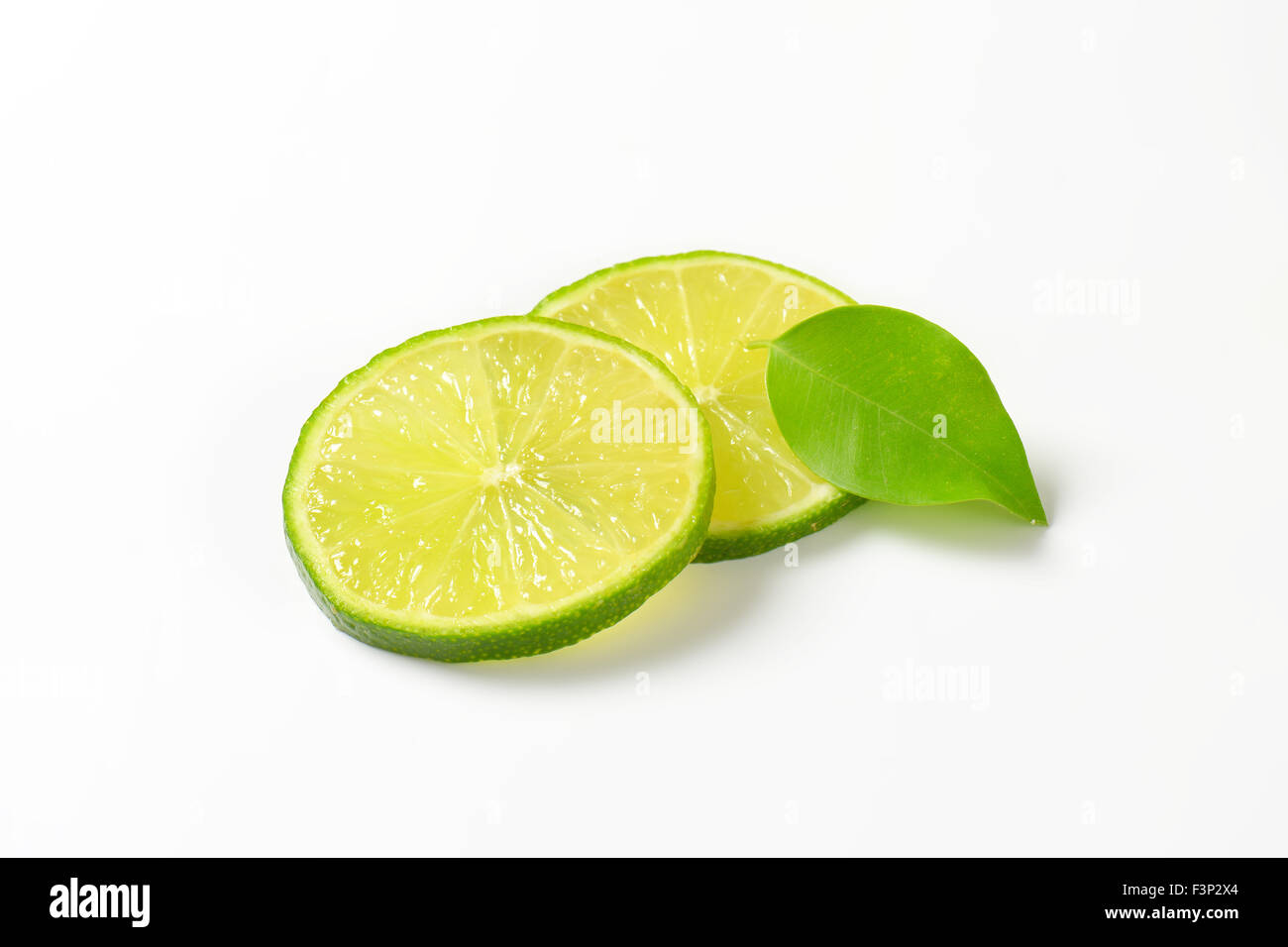 two lime slices with leaf on white background Stock Photo - Alamy