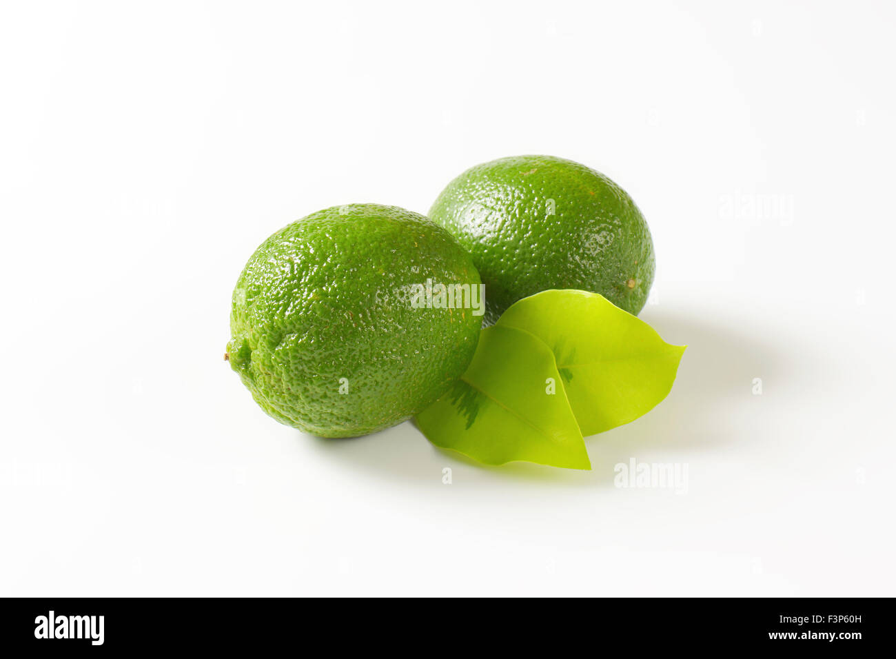 two limes with leaves on white background Stock Photo - Alamy
