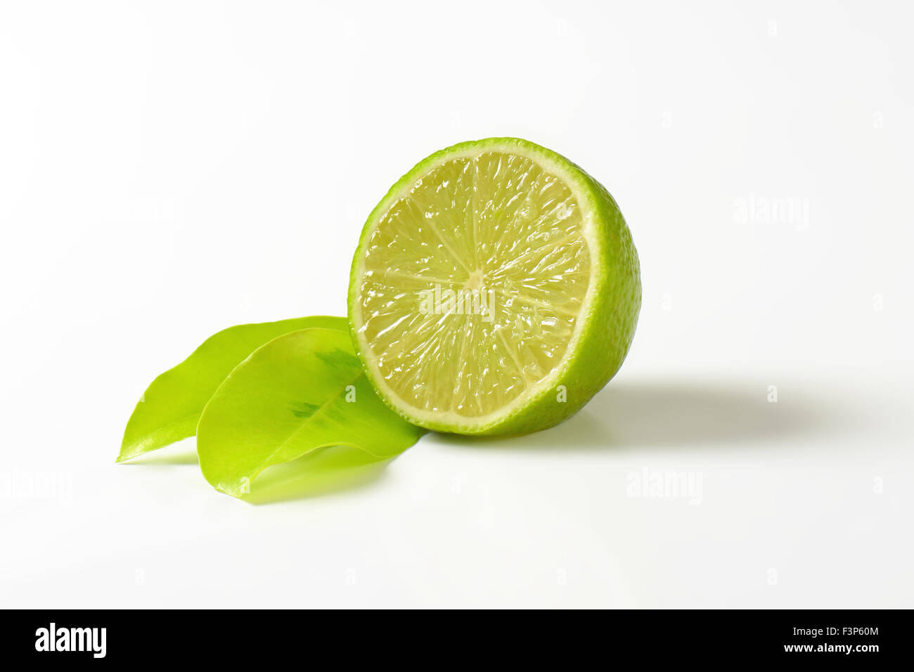 half a lime with leaves on white background Stock Photo - Alamy