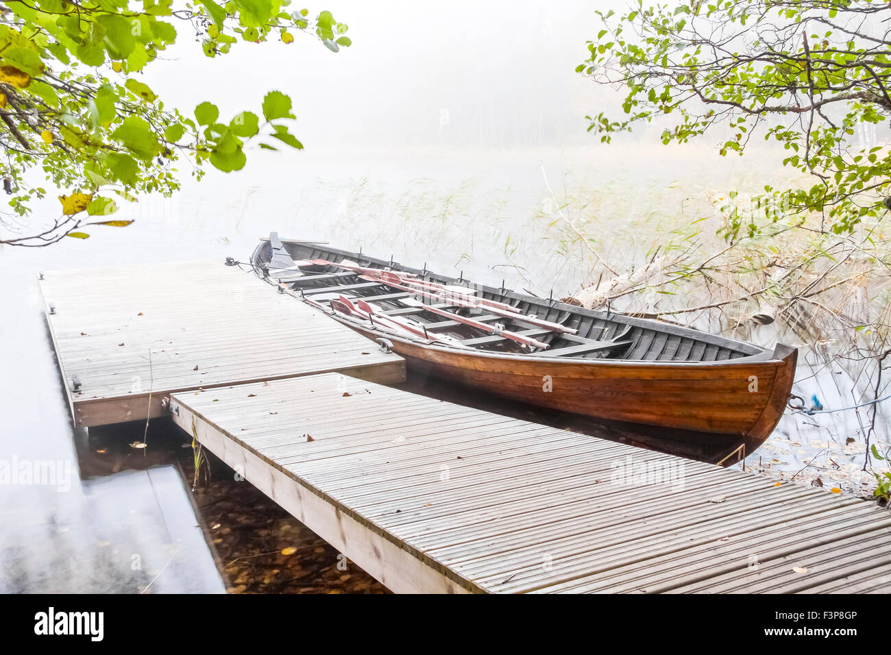 Long wood oar boat parked next to floating quay in a mist Stock Photo ...
