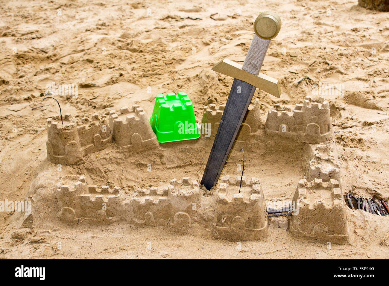 A sandcastle with a toy sword sticking in the middle Stock Photo - Alamy