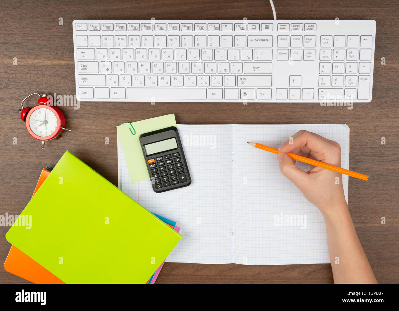 Humans hand writing in copy book with calculator Stock Photo - Alamy