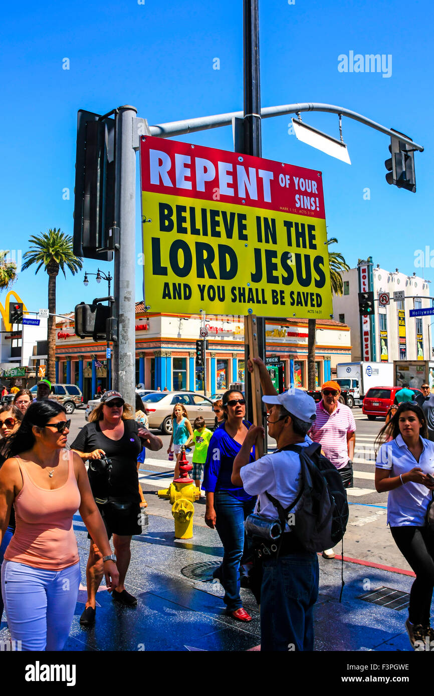 Man holding religious banner as people walk past him along Hollywood ...
