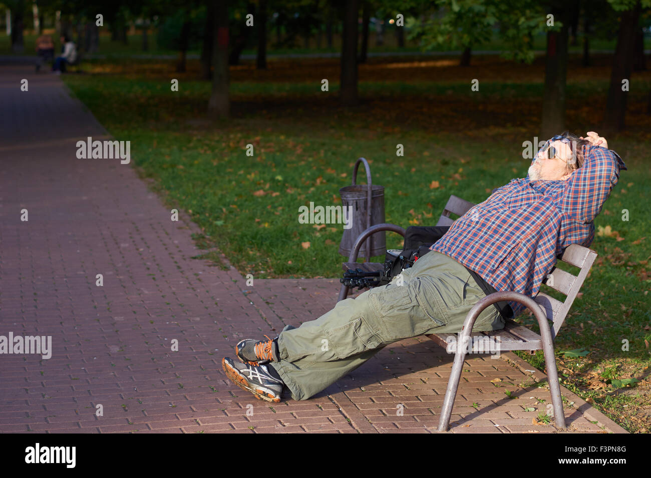 Man has rest in autumn park under the sun Stock Photo - Alamy