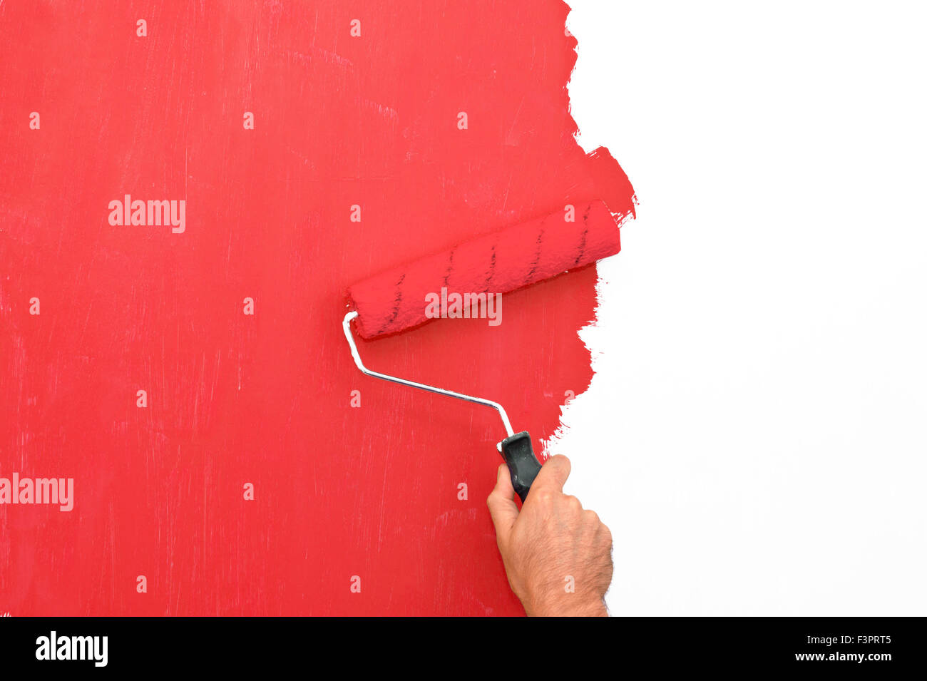 Painting a wall using a roller with red paint Stock Photo - Alamy