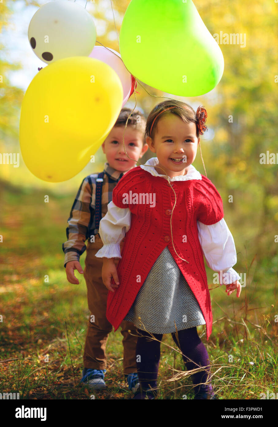 two little kids playing with balloons in the park in autumn Stock Photo ...