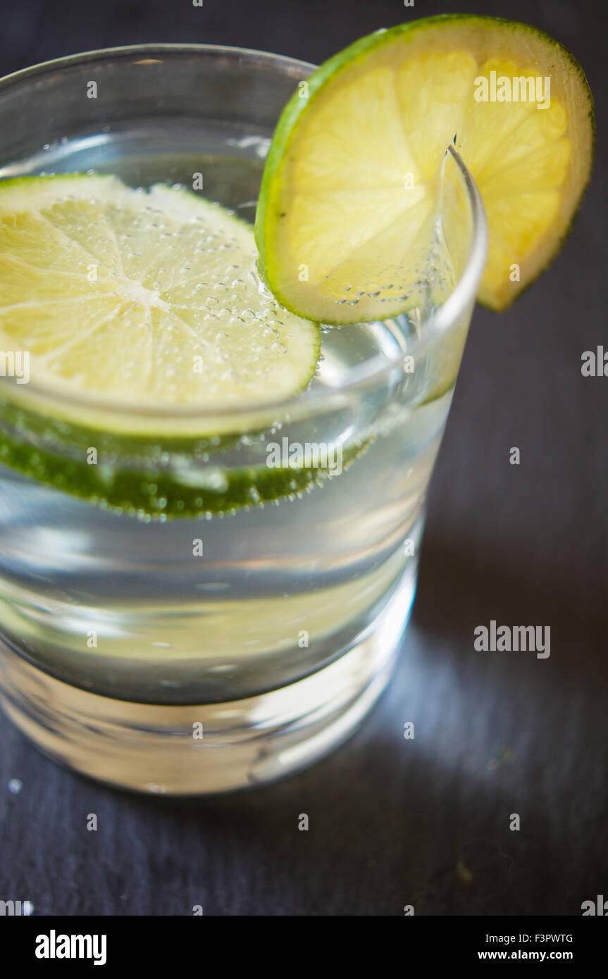 Glass of water with lime on the black stone background Stock Photo - Alamy