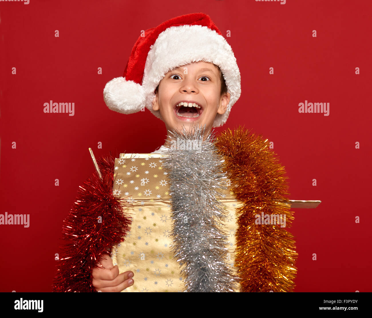 winter holiday christmas concept - boy in santa hat having fun on red ...