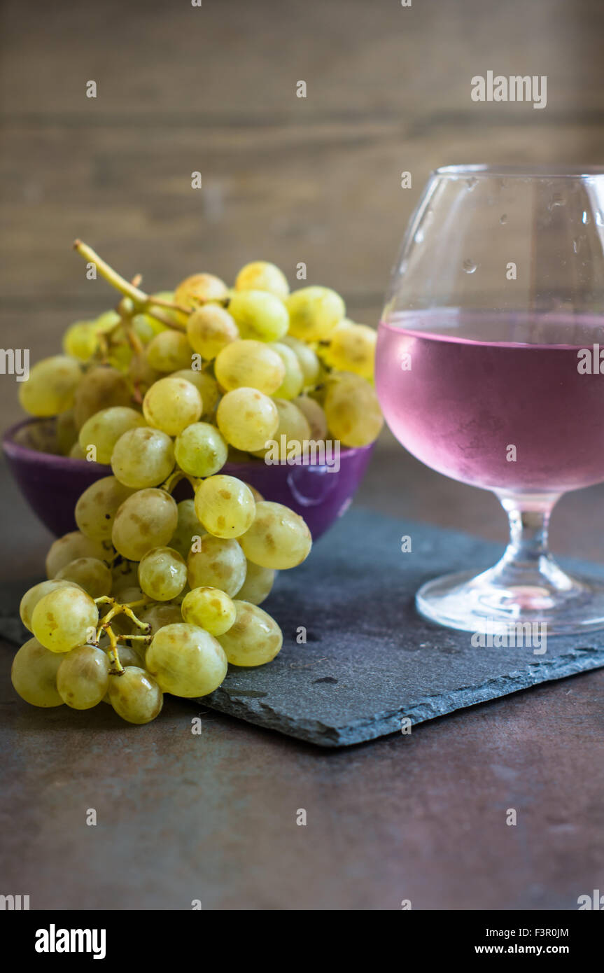 Glass of rose wine and ripe grapes on vintage background. Selective ...