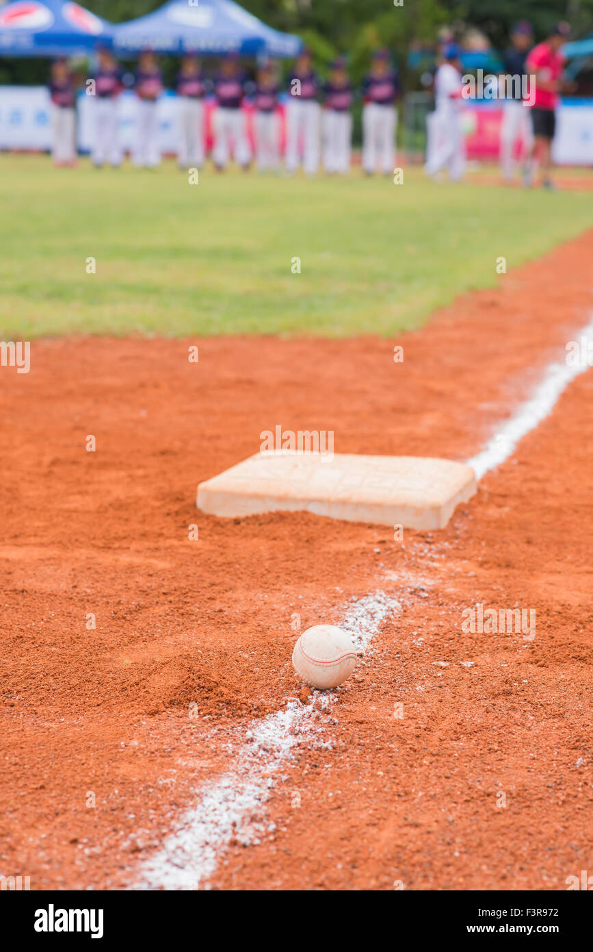 baseball and base on baseball field with players and coach on ...