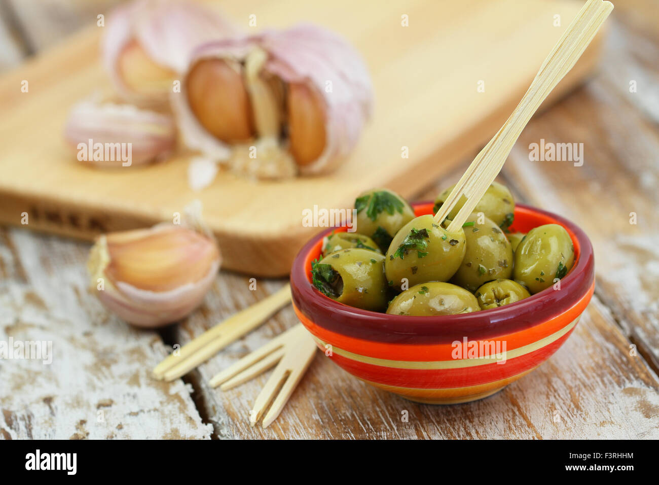 Fresh green olives with garlic in traditional clay bowl on rustic ...