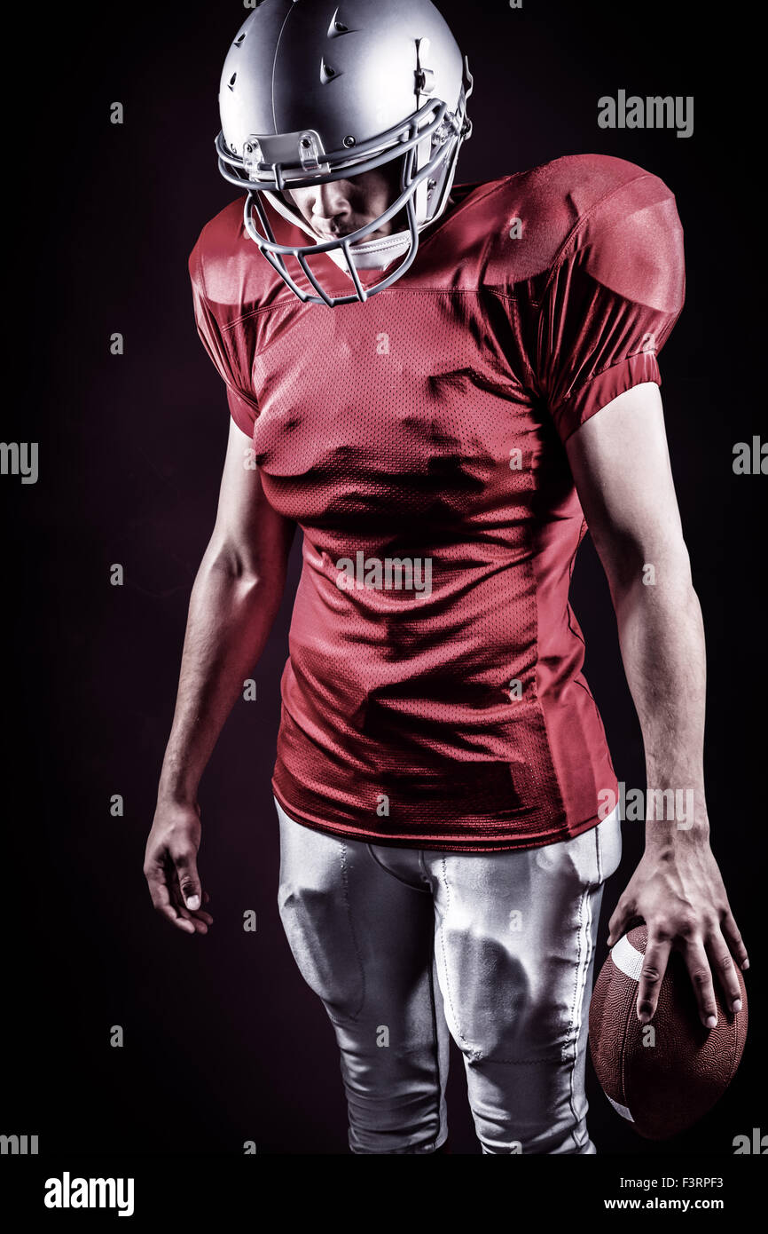 Composite image of american football player looking down while standing ...