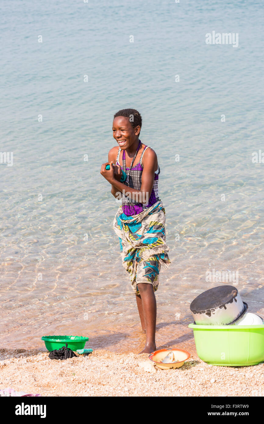Smiling young African woman washing clothes on the seashore at Kaya ...