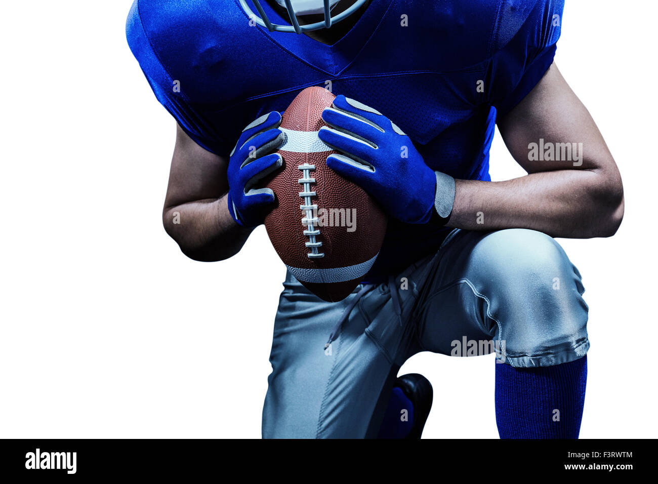 Mid section of American football player kneeling while holding ball ...