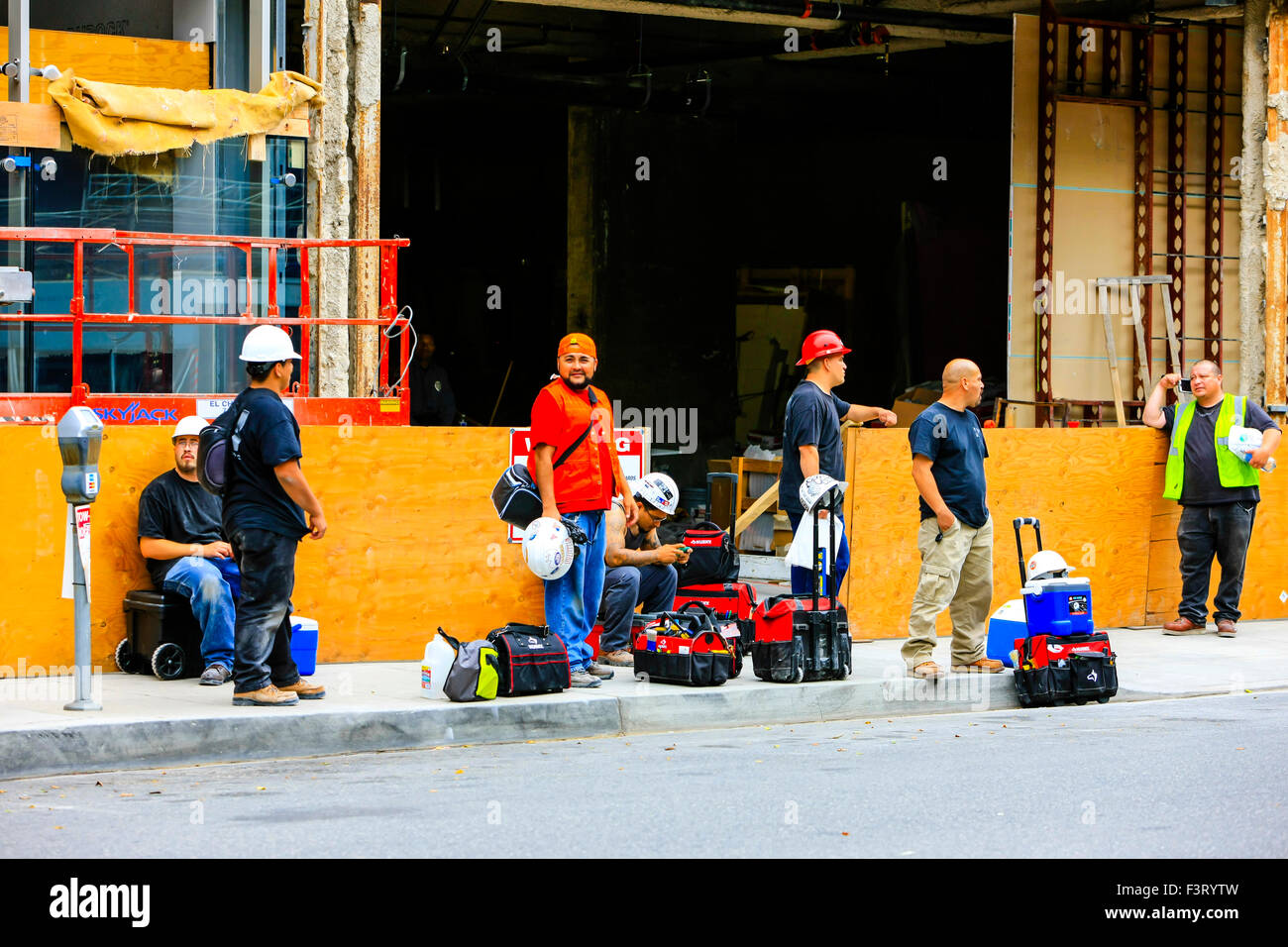 Construction workers wait at the sidewalk edge for the ride out of ...