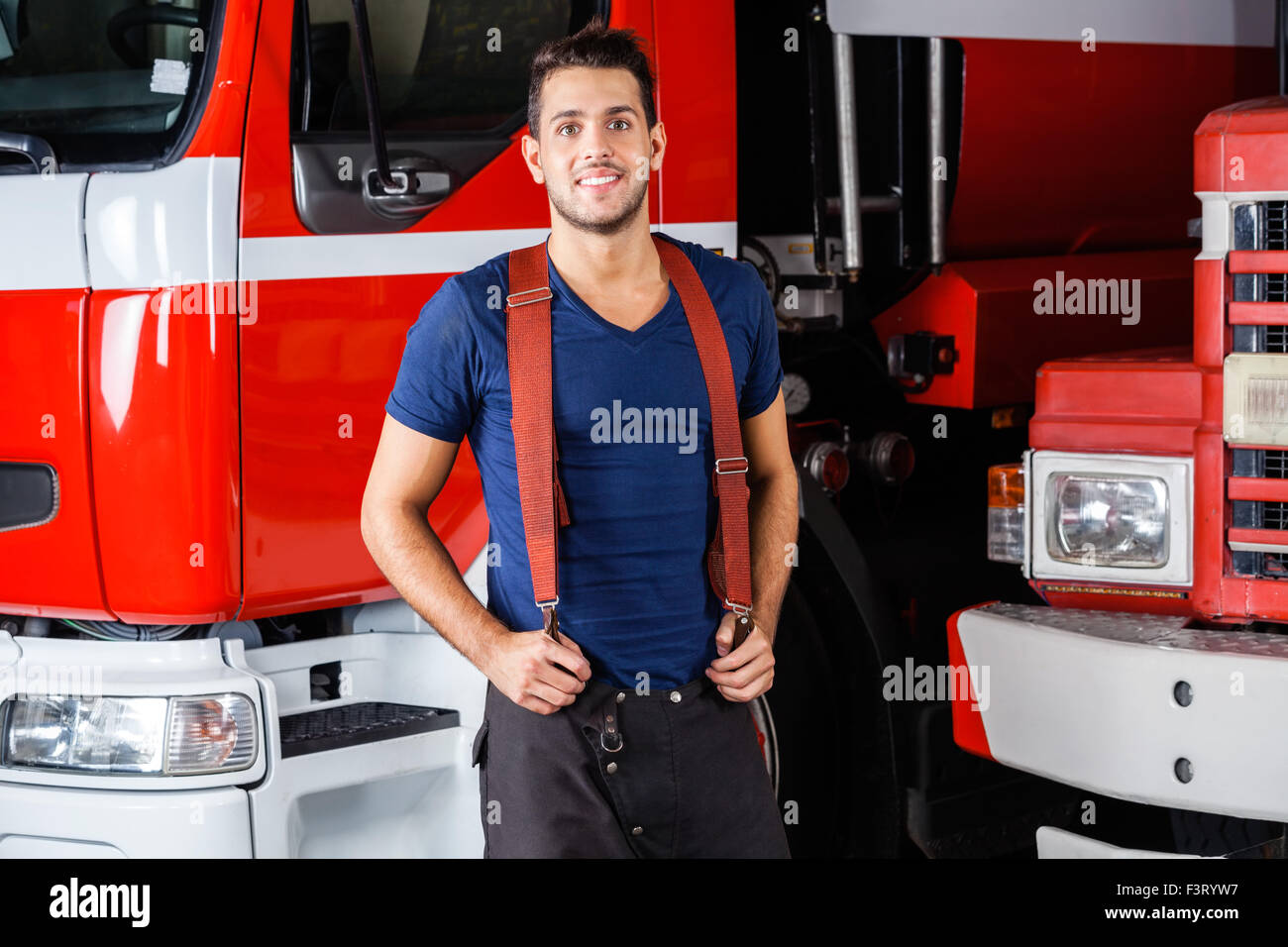 Smiling Fireman Standing Against Trucks Stock Photo - Alamy