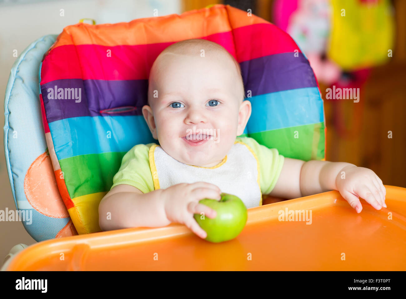 Adorable baby eating apple in high chair. Baby's first solid food Stock ...