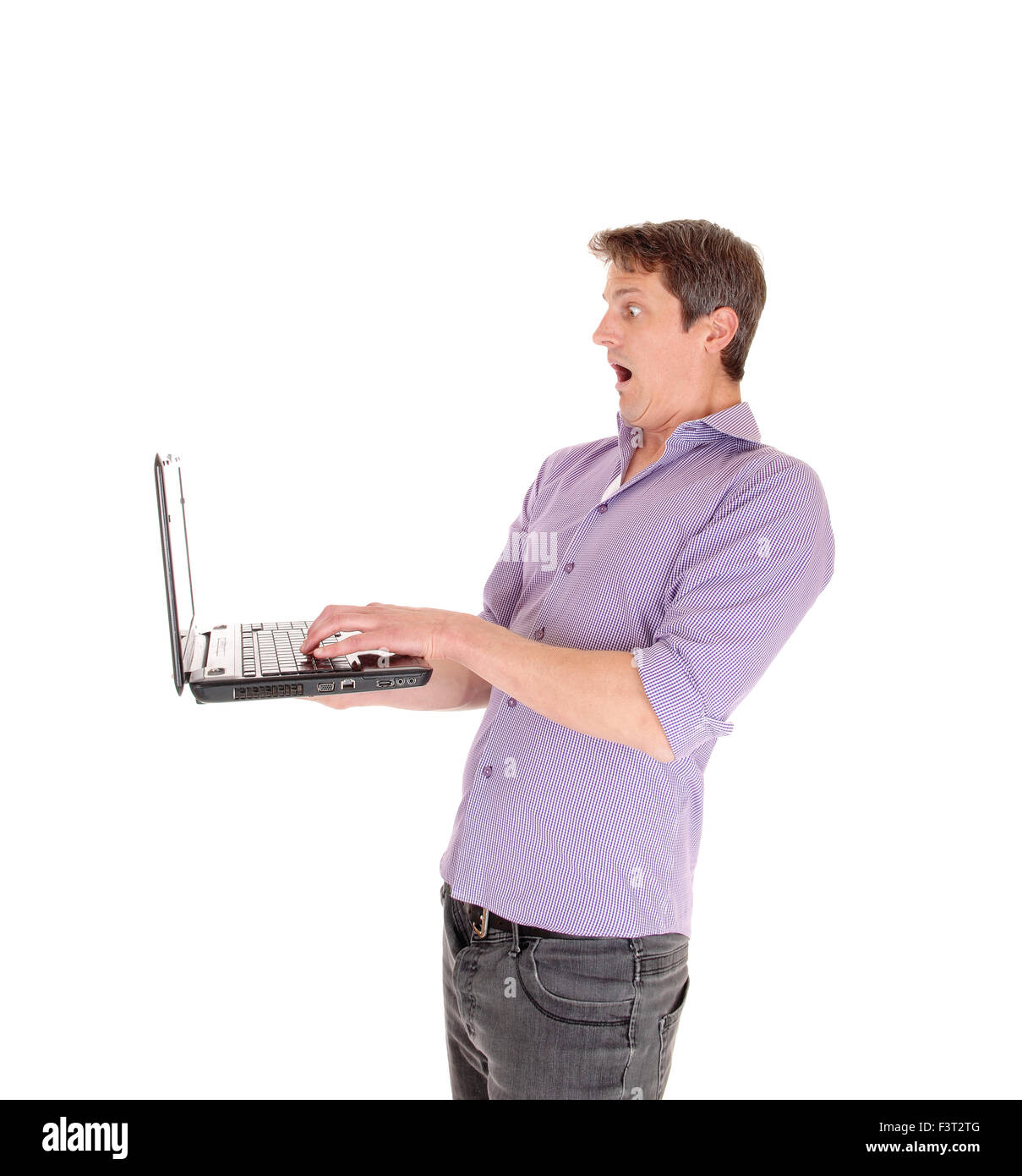 A young man holding his laptop and is surprised what he see's at the ...