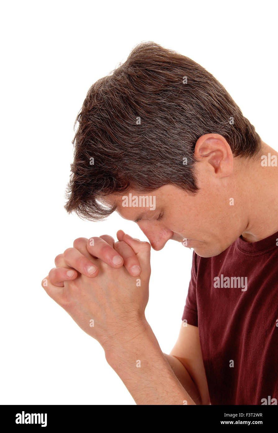 A young man with folded hands praying in closeup, isolated for white ...