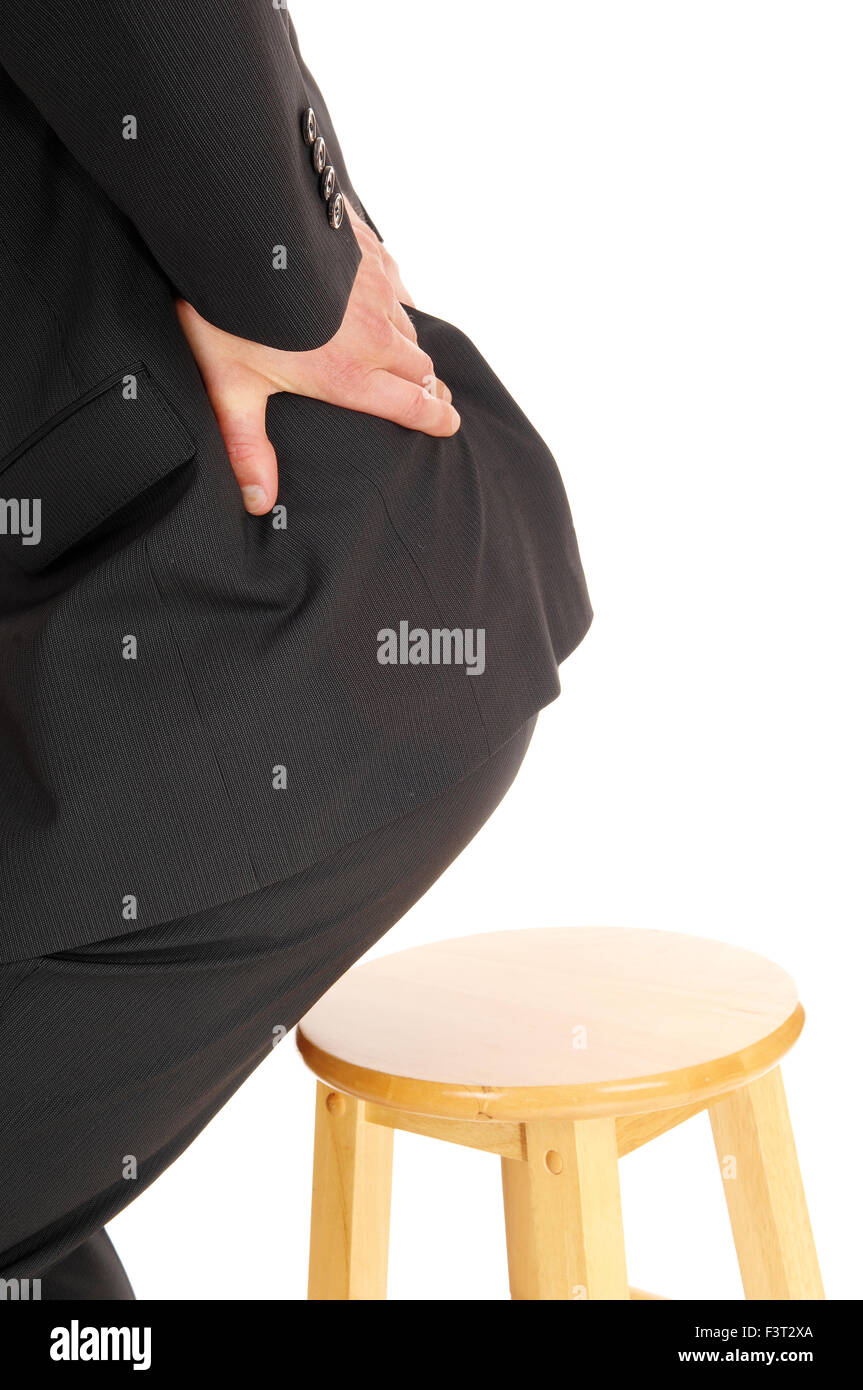 A business man getting up from his chair holding his hand on his back ...
