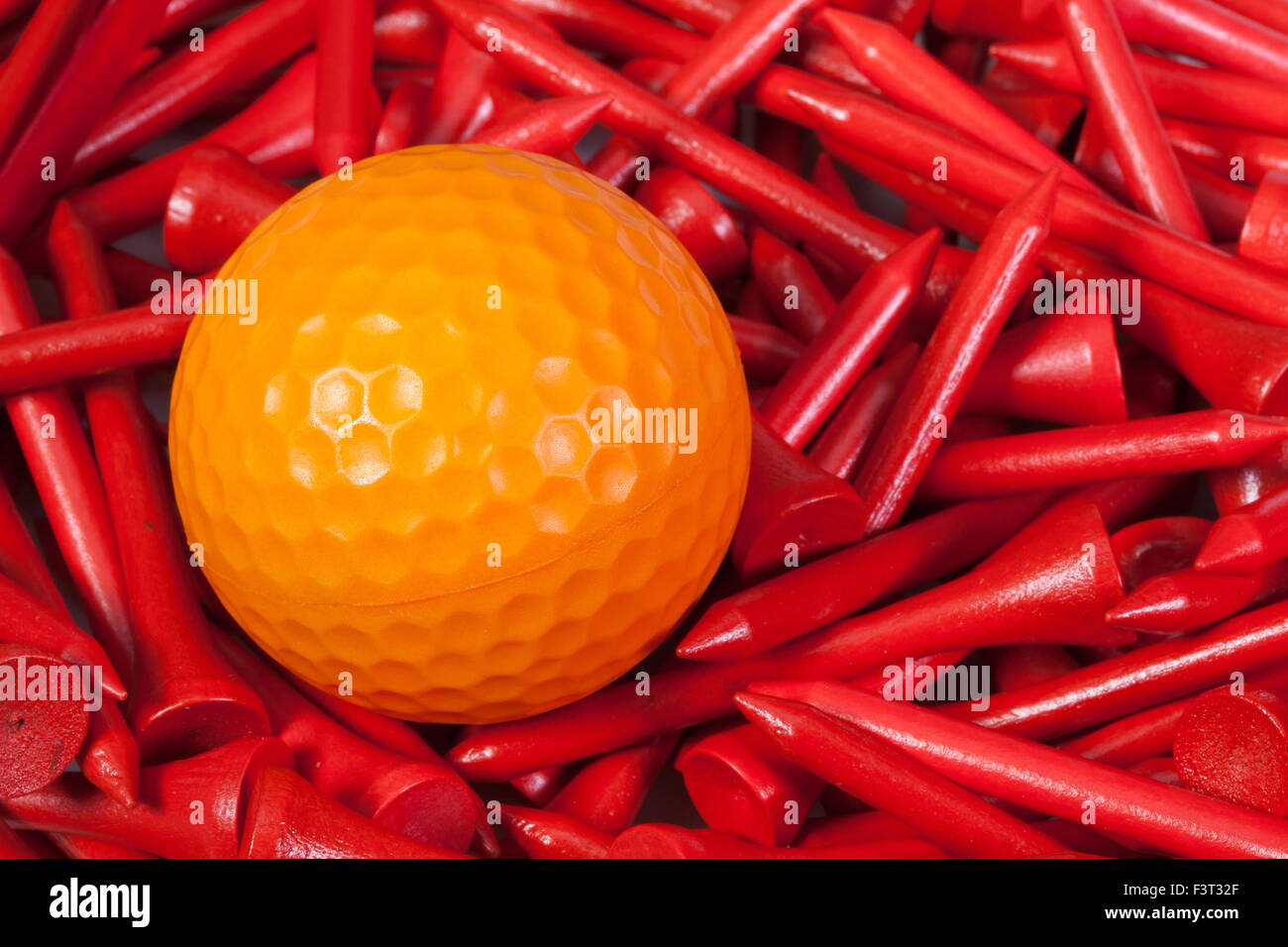 Orange golf ball lying between red wooden golf tees Stock Photo - Alamy