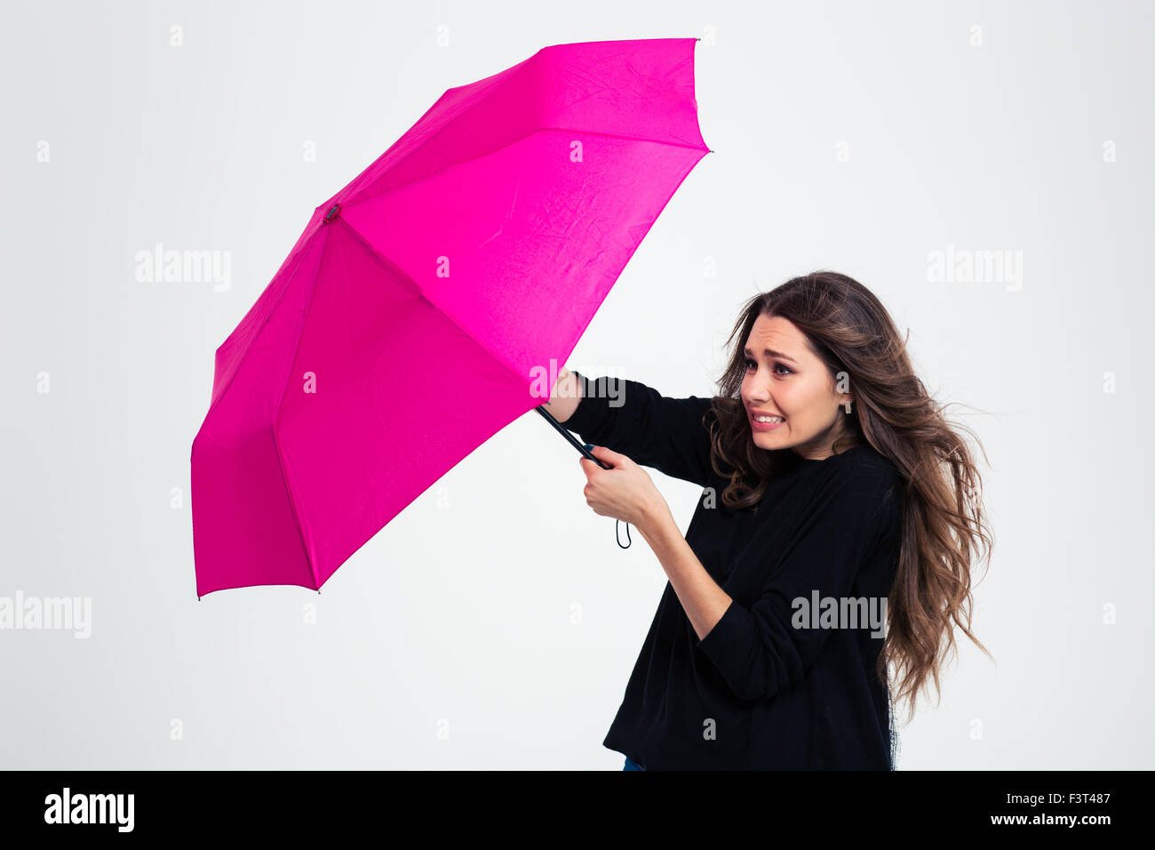 Portrait of a young woman holding umbrella in a strong wind isolated on ...