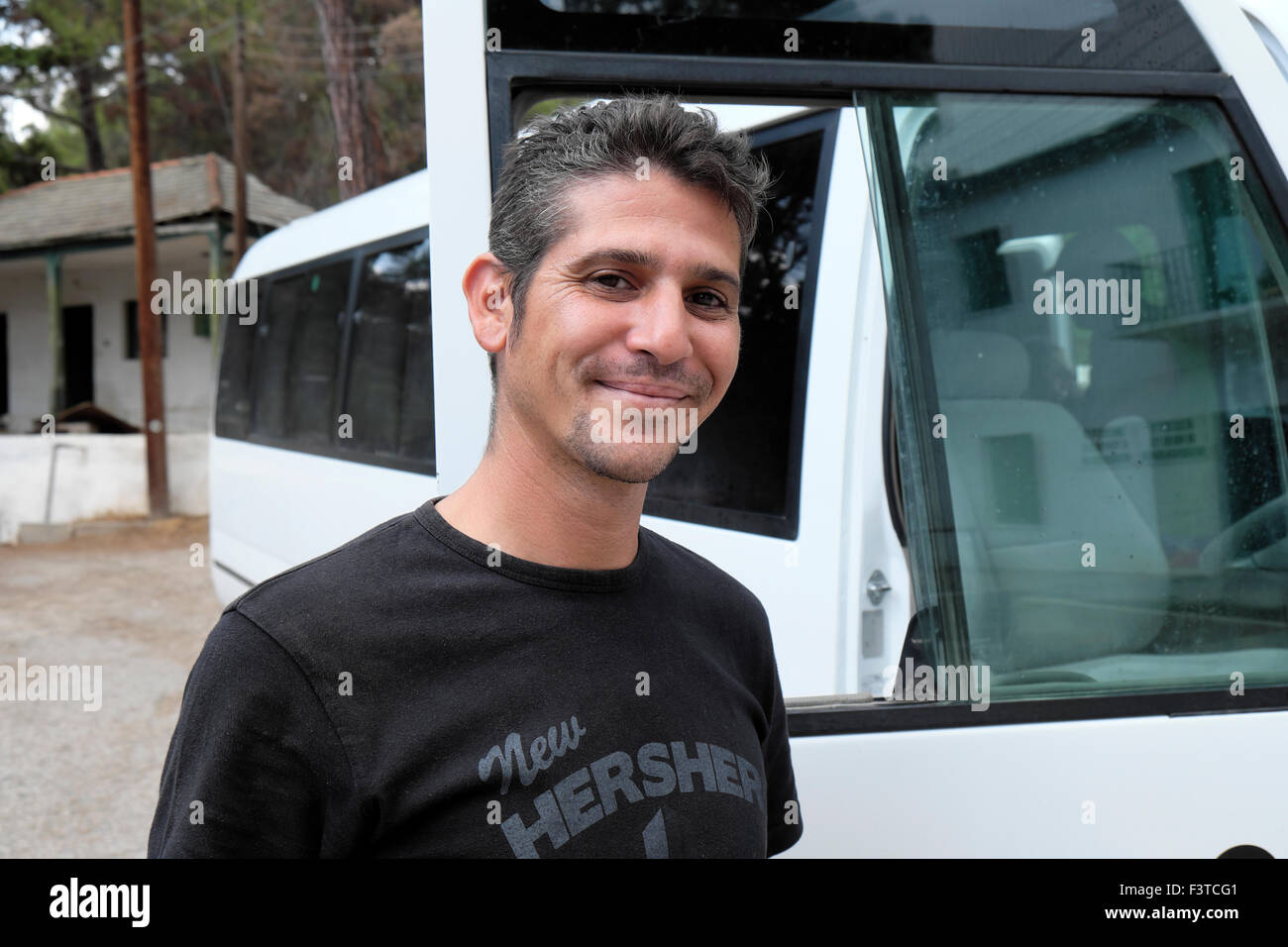 A handsome friendly young tourist bus driver smiling standing next to a ...