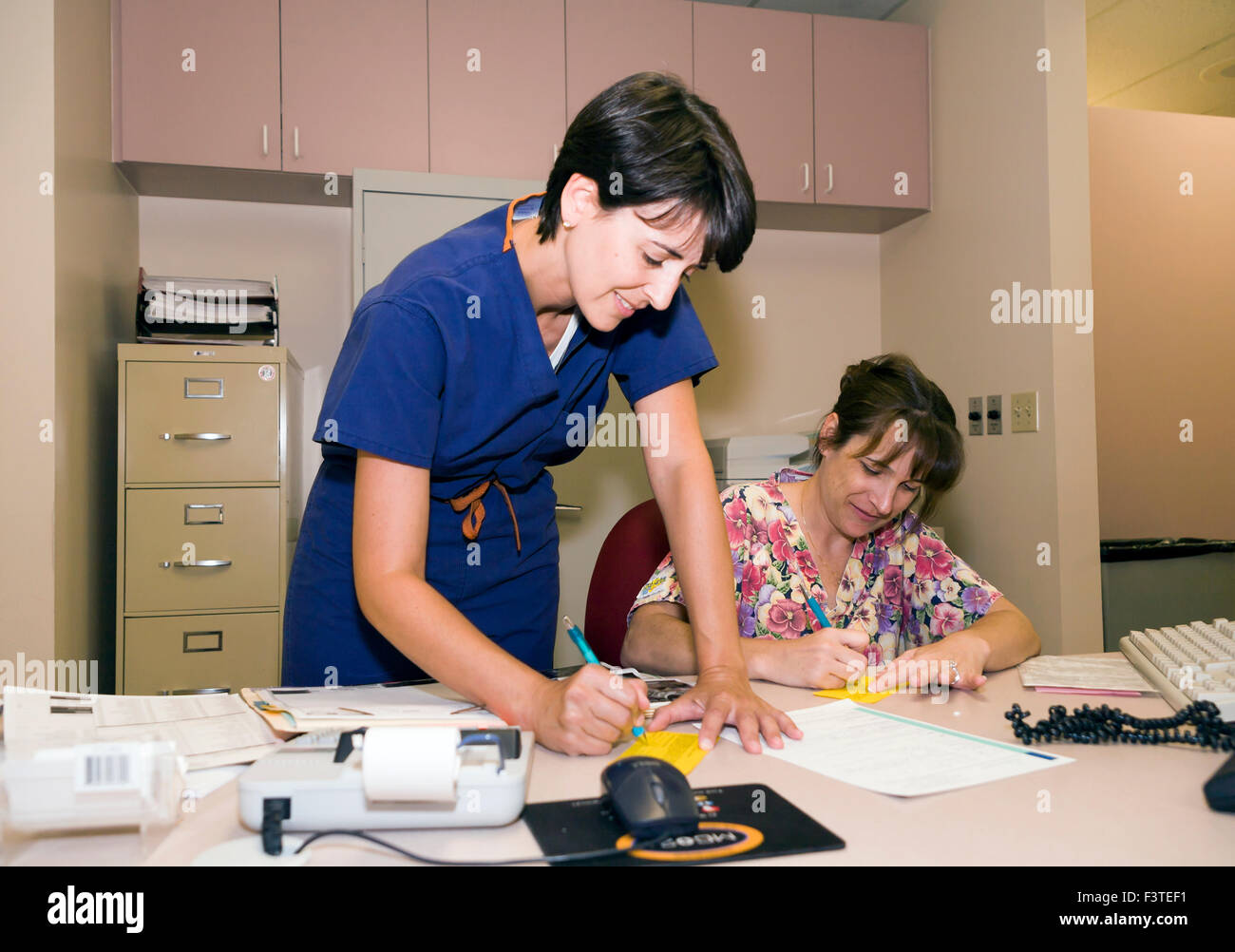 Female Physician and receptionist working together in doctors office ...