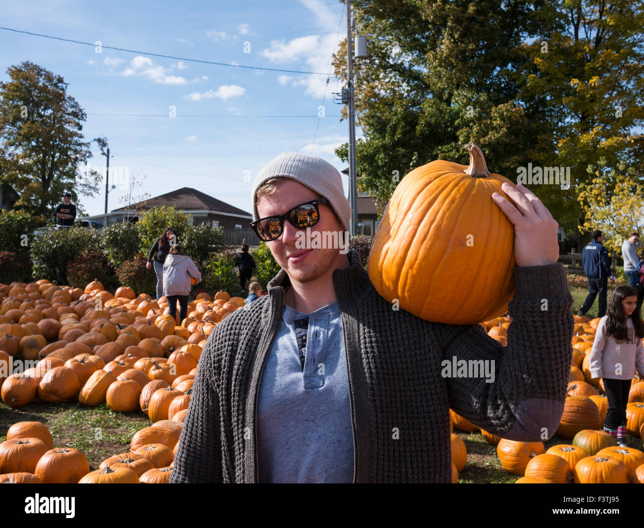 Shoppers carrying pumpkin on shoulders from farmers market during ...