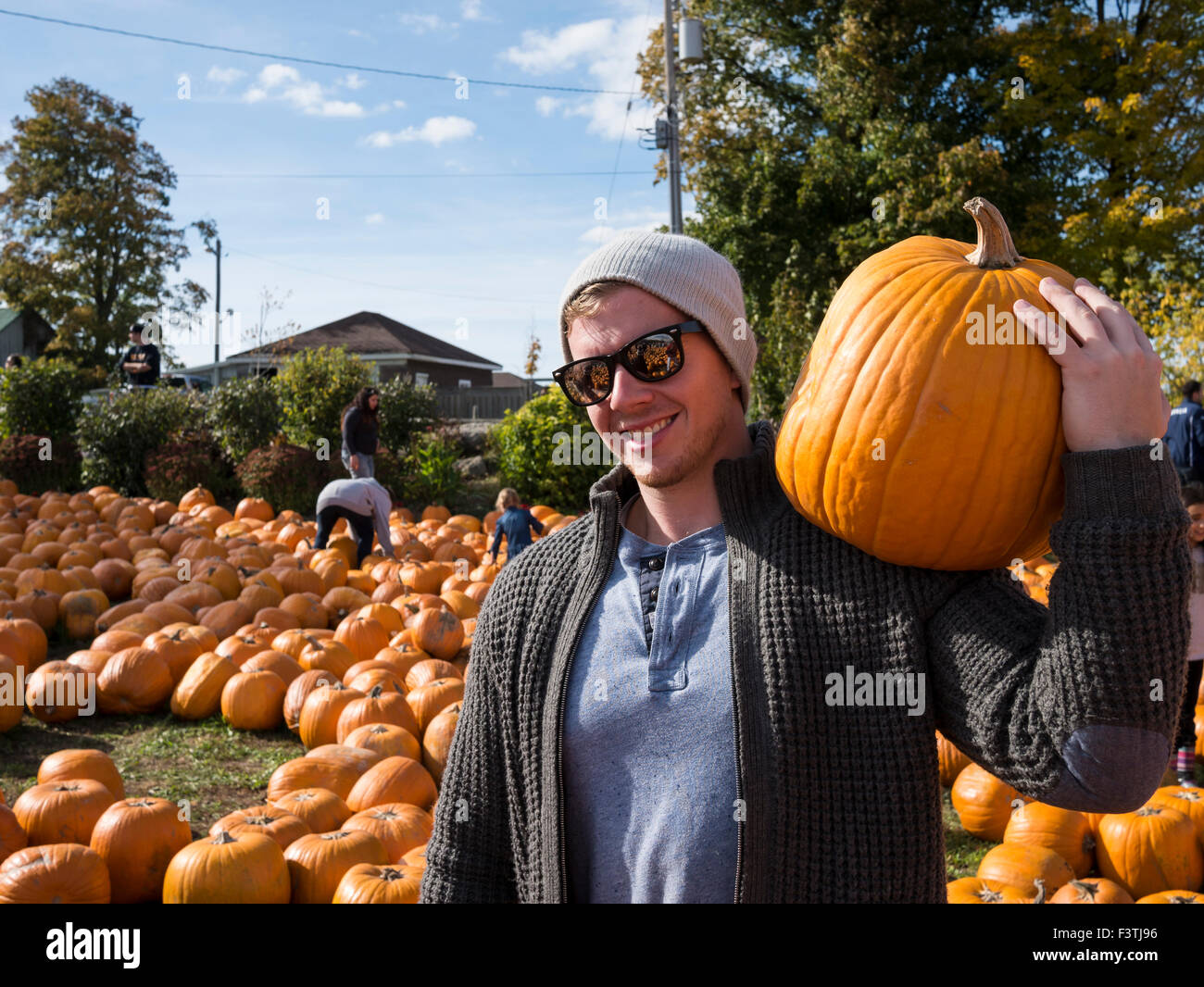Shoppers carrying pumpkin on shoulders from farmers market during ...