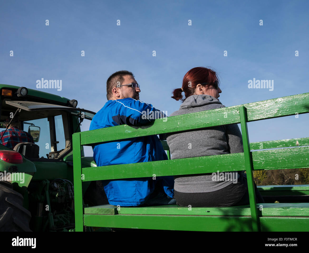 Couple traveling by tractor trailer in a farm Stock Photo - Alamy