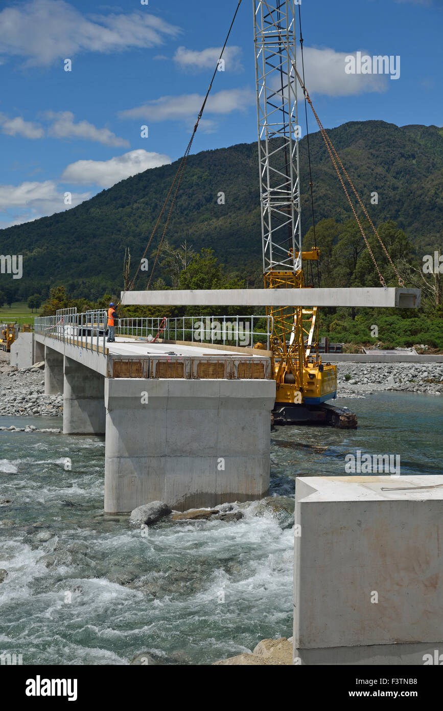 Builders construct a concrete bridge over a small river in Westland ...