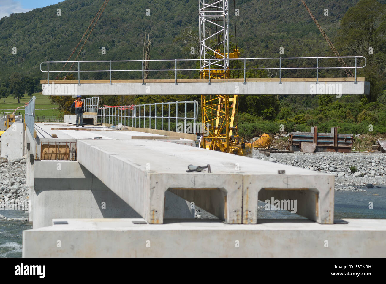 Builders construct a concrete bridge over a small river in Westland ...