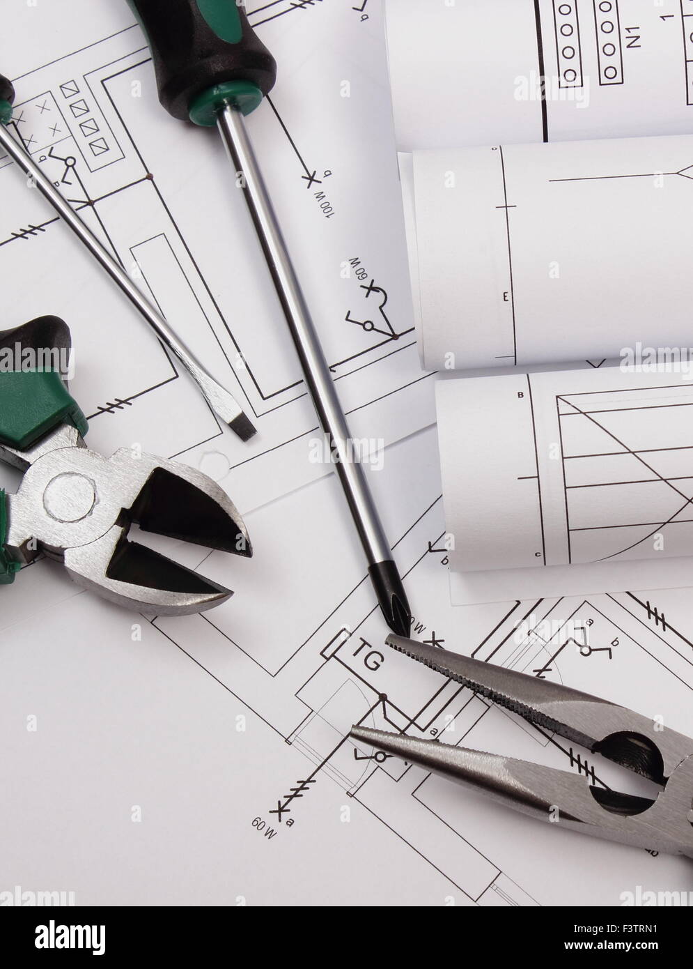 Rolls of diagrams, metal pliers and screwdriver on electrical ...