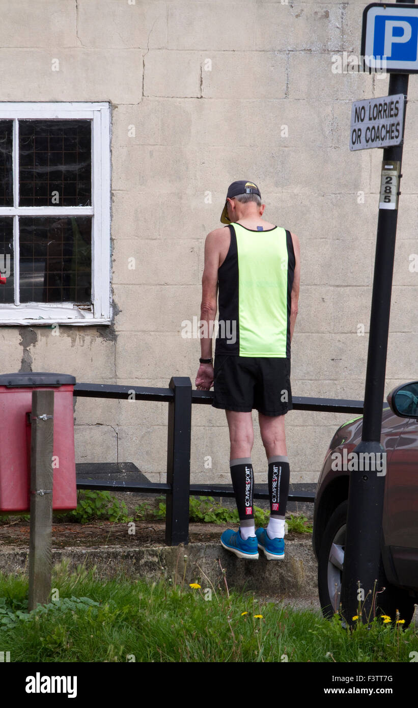 Runner stands on curb to stretch hamstrings Stock Photo - Alamy