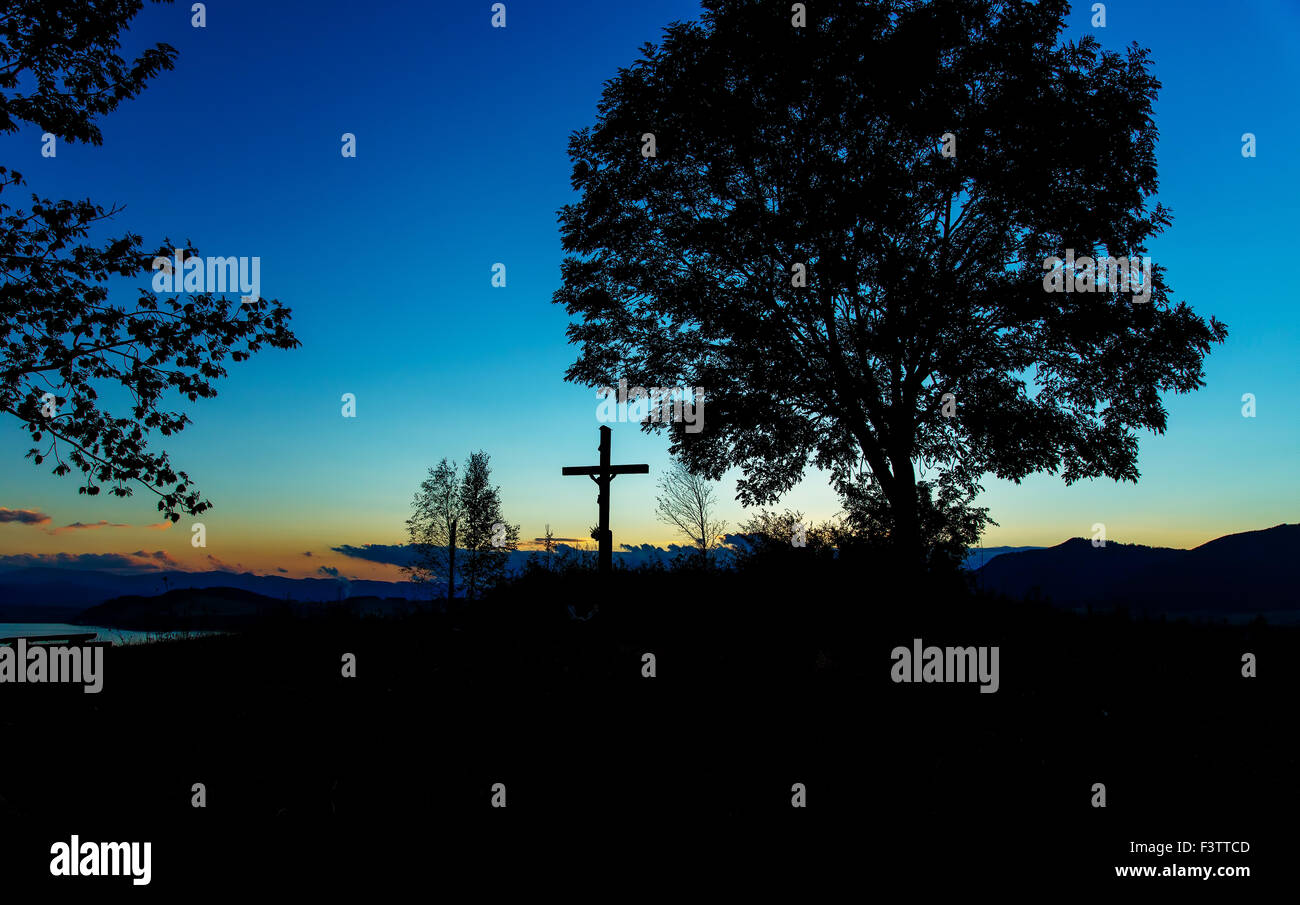wooden crosses sit upon a hill in the sunset with tree and lake Stock ...