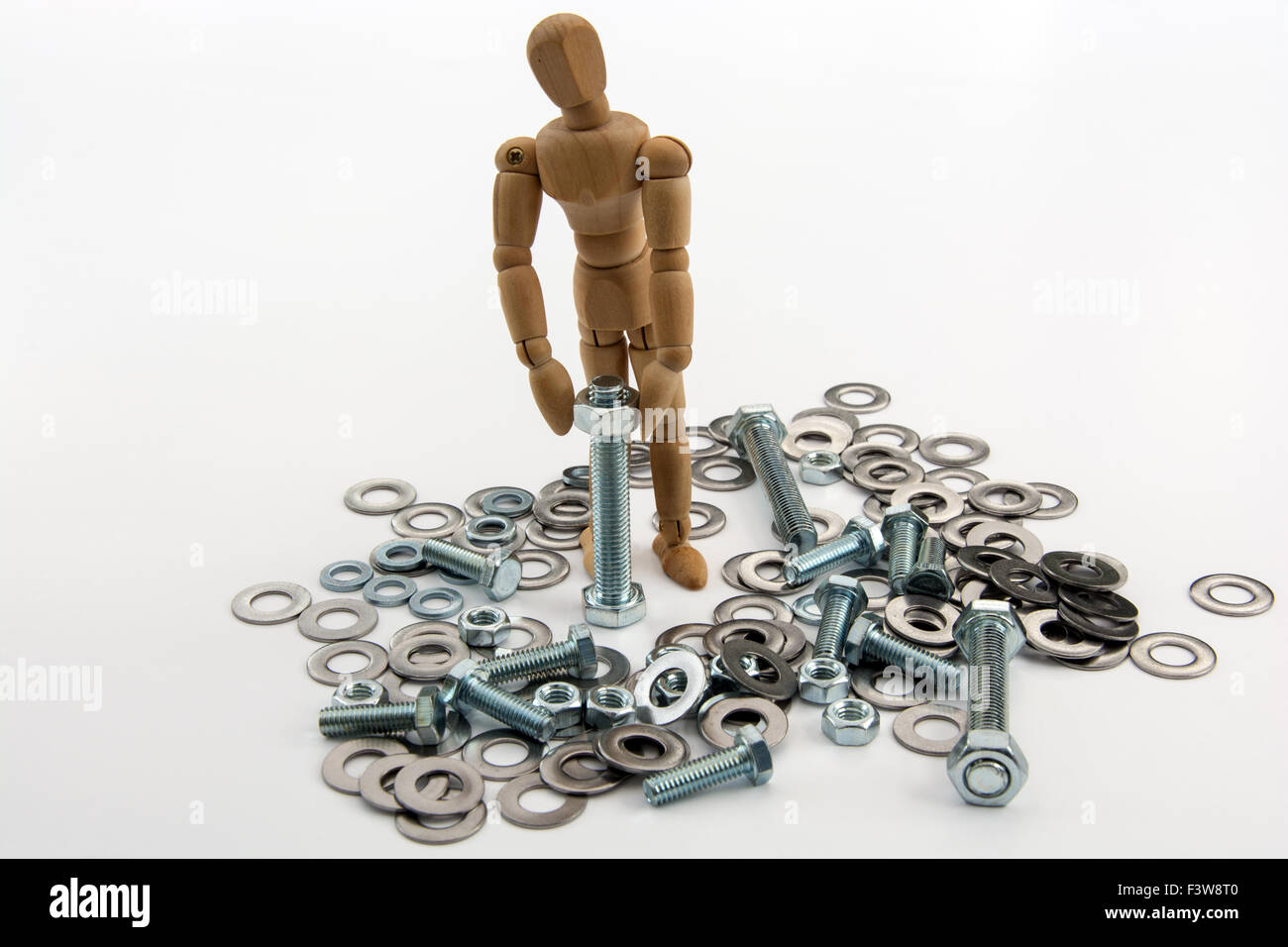 A wooden manikin turning a nut on a bolt Stock Photo - Alamy