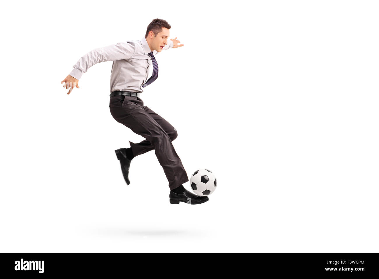 Full length profile shot of a young businessman kicking a football ...